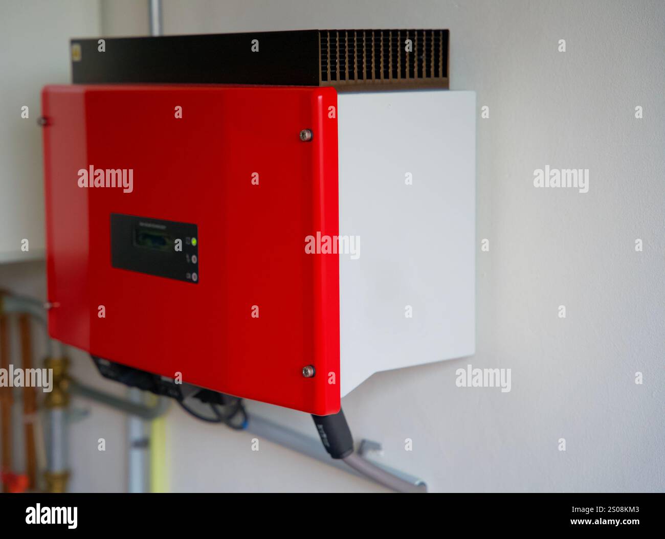 Close up of a red solar power inverter mounted to a white wall. Red ...