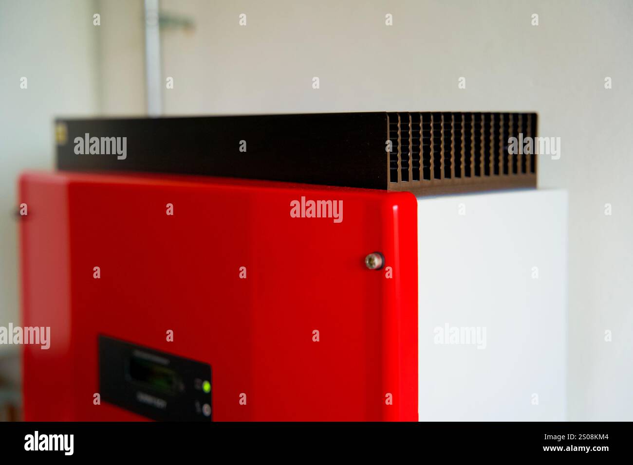 Close up of a red solar power inverter mounted to a white wall. Red ...