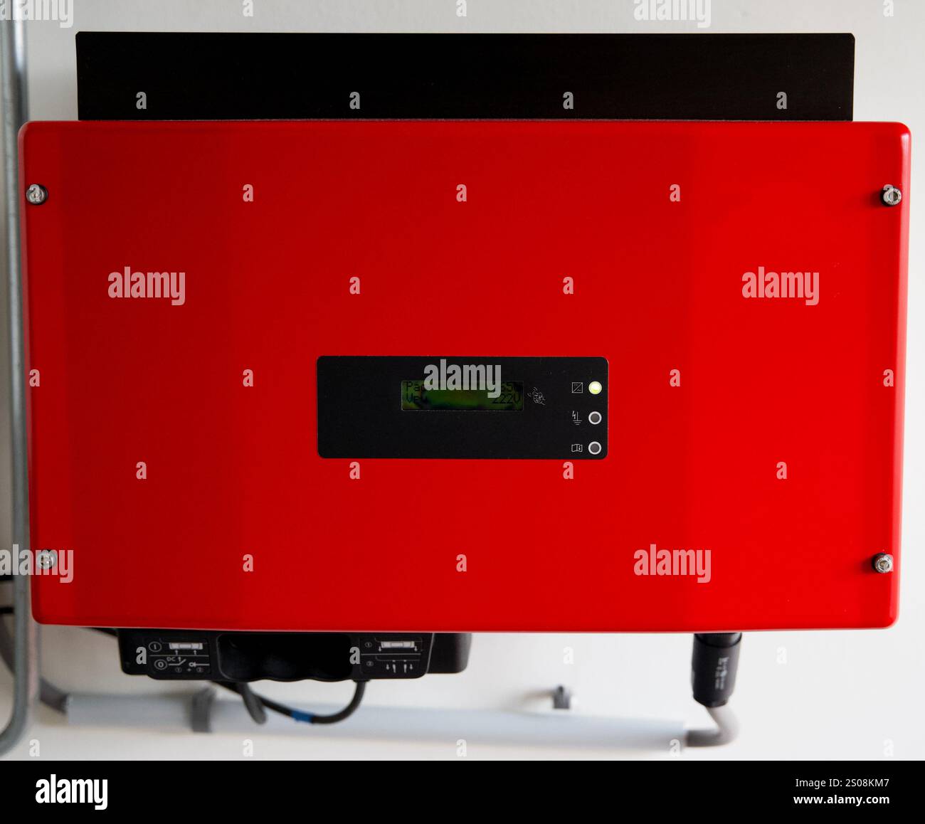 Close up of a red solar power inverter mounted to a white wall. Red ...