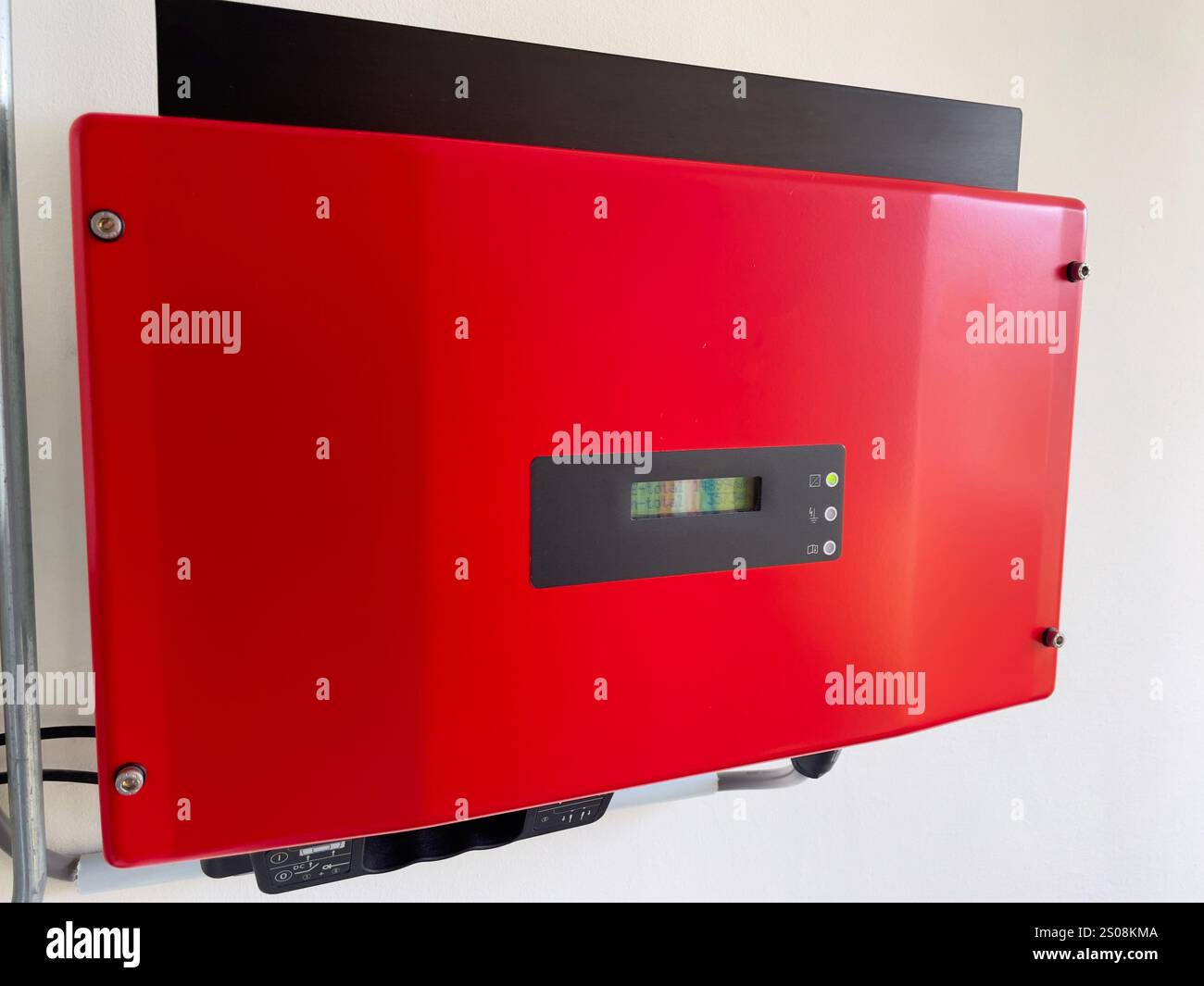 Close up of a red solar power inverter mounted to a white wall. Red ...