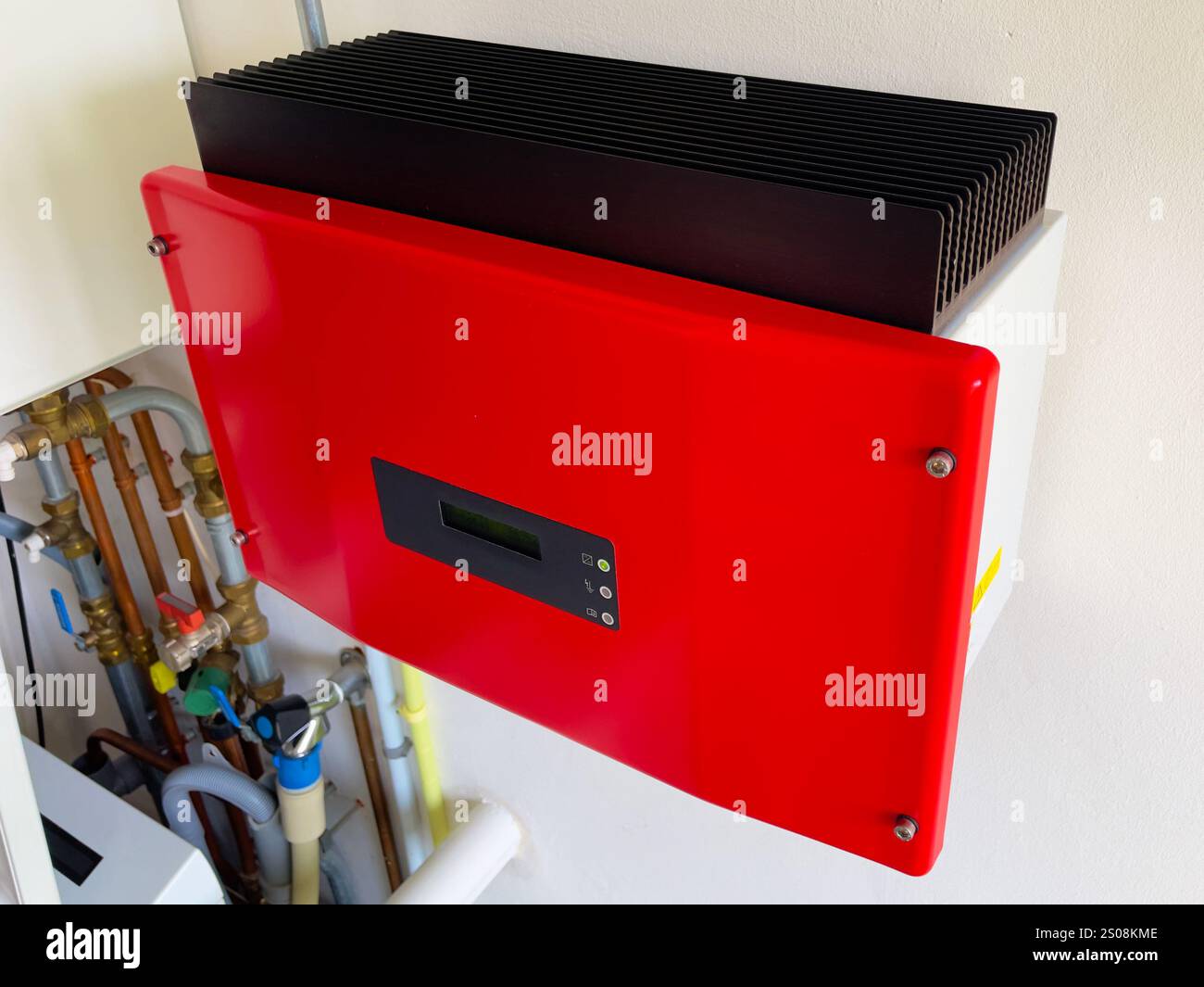 Close up of a red solar power inverter mounted to a white wall. Red ...