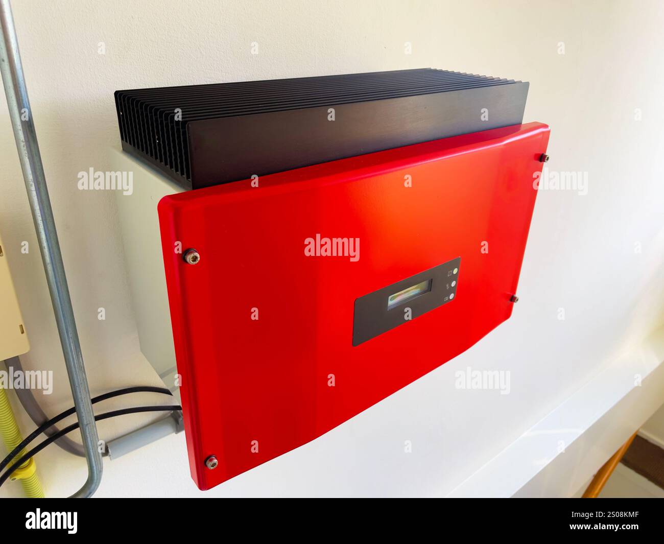 Close up of a red solar power inverter mounted to a white wall. Red ...