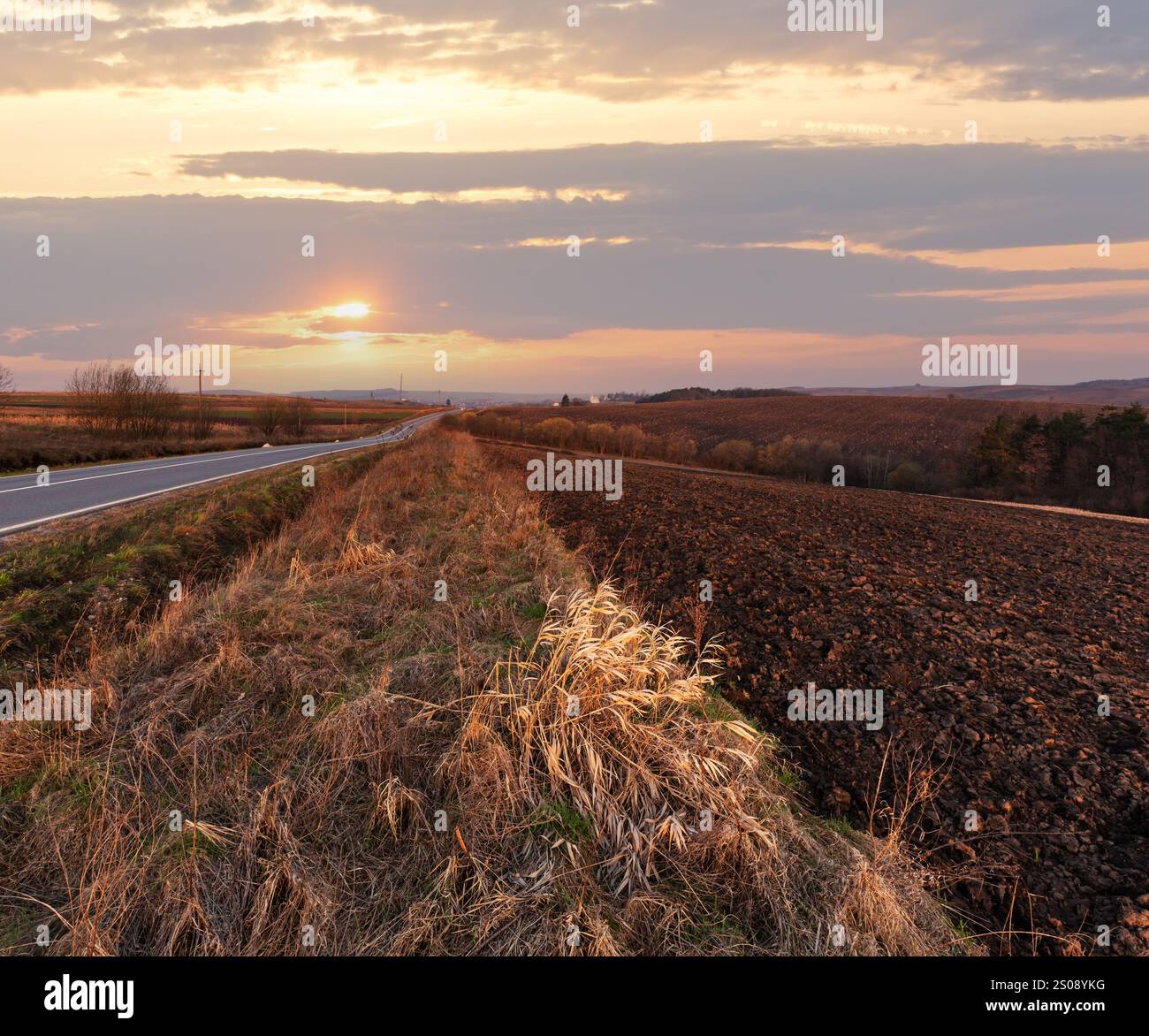 Spring sunrise rural country landscape with plowed agricultural fields, groves, road and village ...