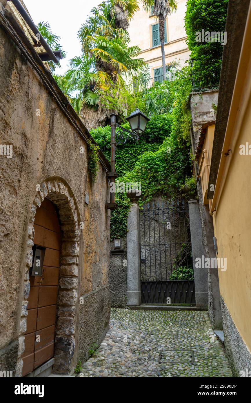 Narrow cobblestone alleyway with rustic stone walls, an arched wooden ...