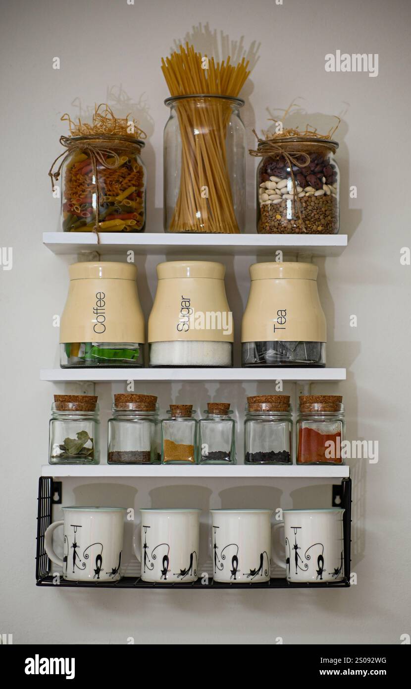 Modern kitchen shelves showing jars with pasta, legumes, coffee, sugar ...