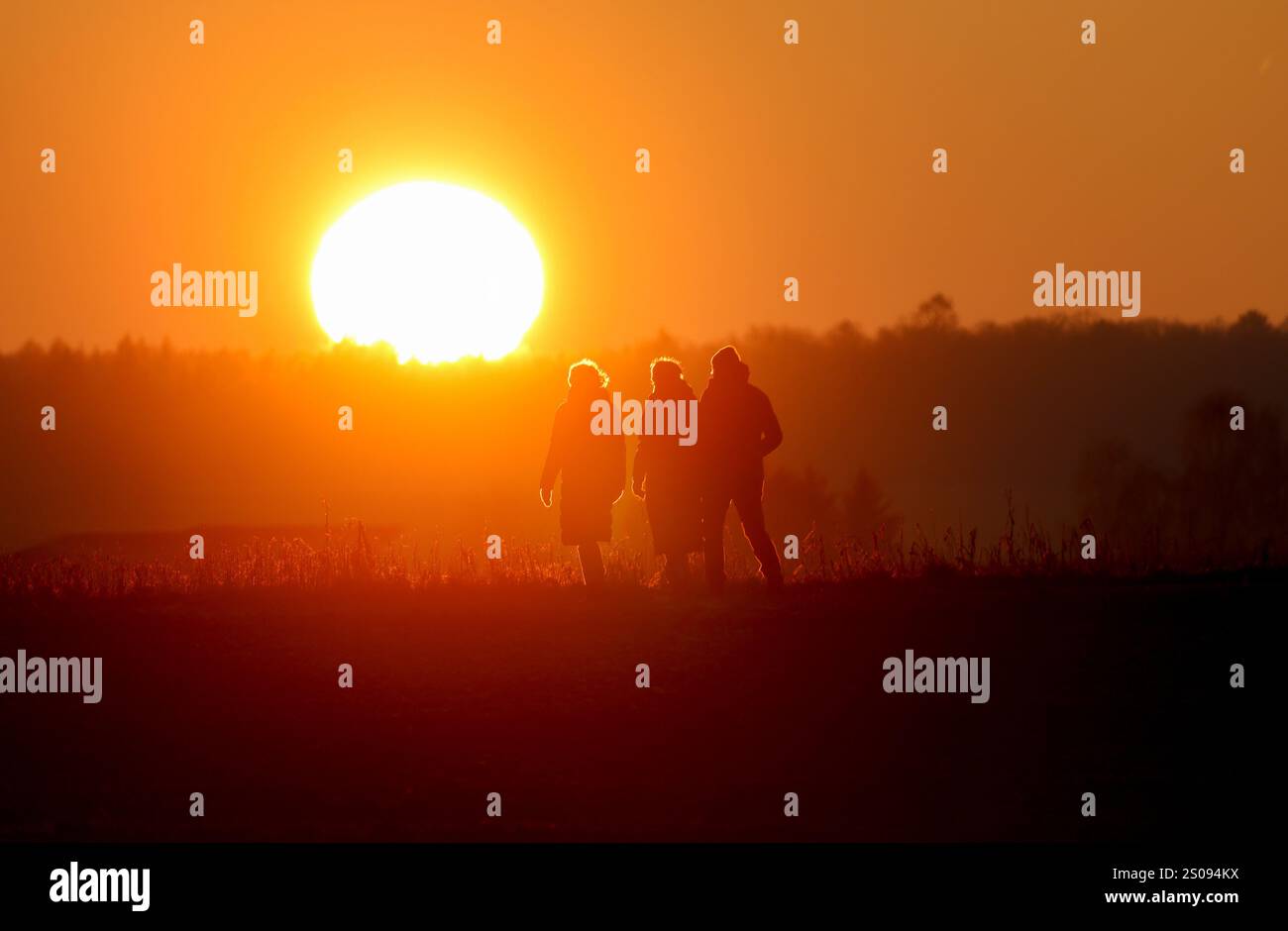 Altheim, Germany. 26th Dec, 2024. Walkers run towards the setting sun. Credit: Thomas Warnack ...