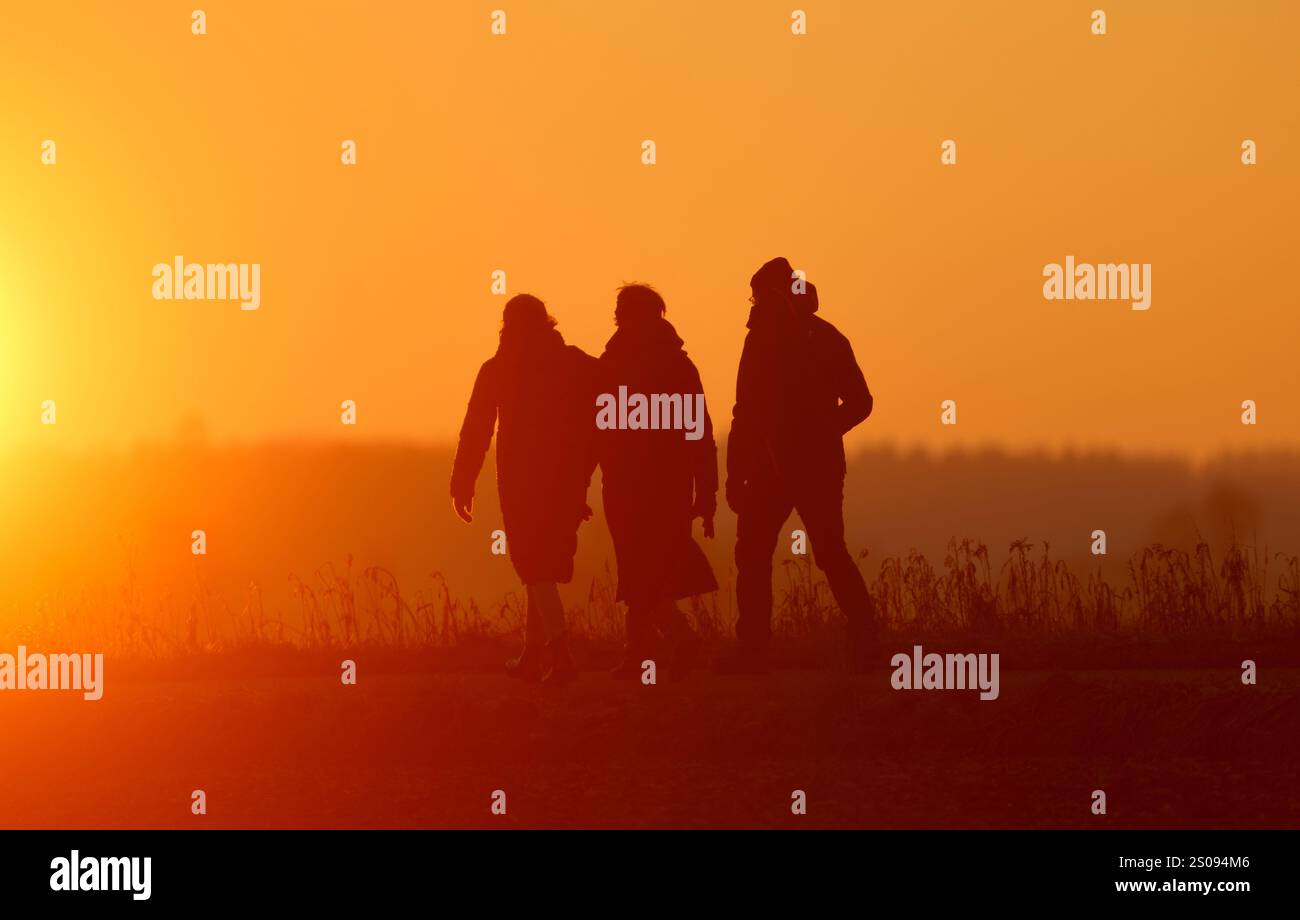 Altheim, Germany. 26th Dec, 2024. Walkers run towards the setting sun. Credit: Thomas Warnack ...