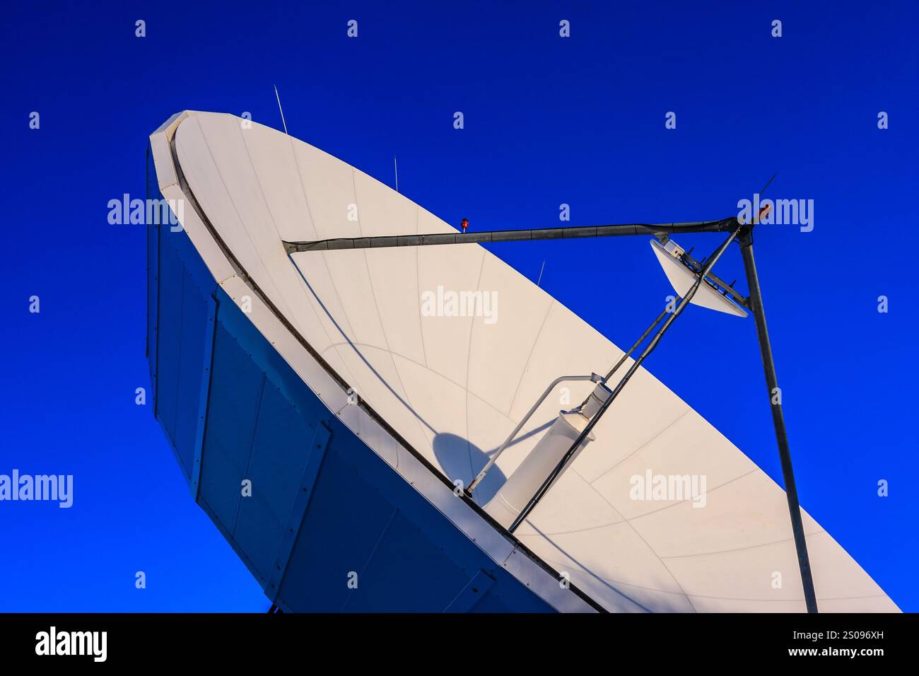 A large satellite dish is pointed towards the sky. The dish is white ...