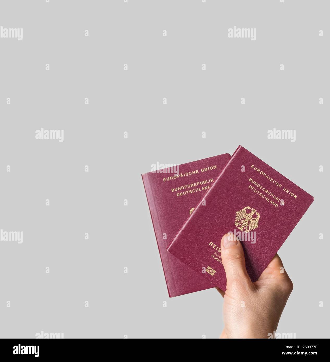 A close-up shot of a hand holding German passports, including a child's ...