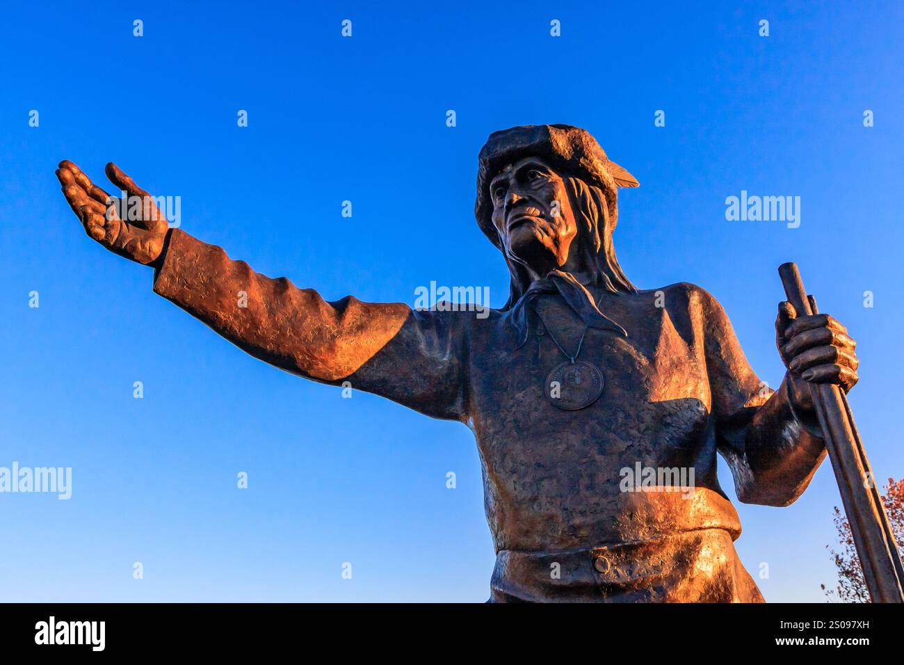 A statue of a Native American man holding a staff. The statue is ...