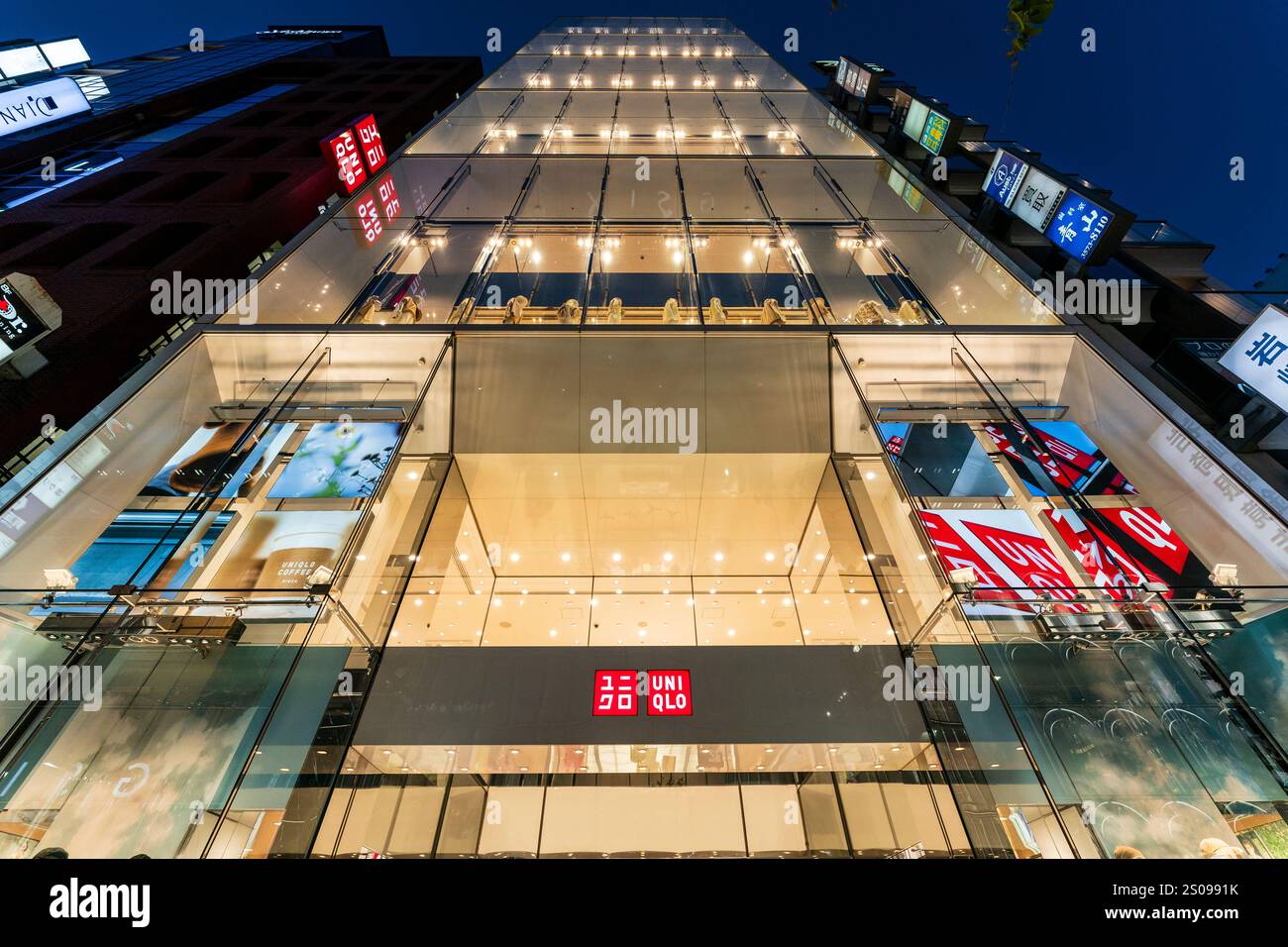 The brightly lit glass facade of the Ginza Uni Qlo flagship store. Low ...