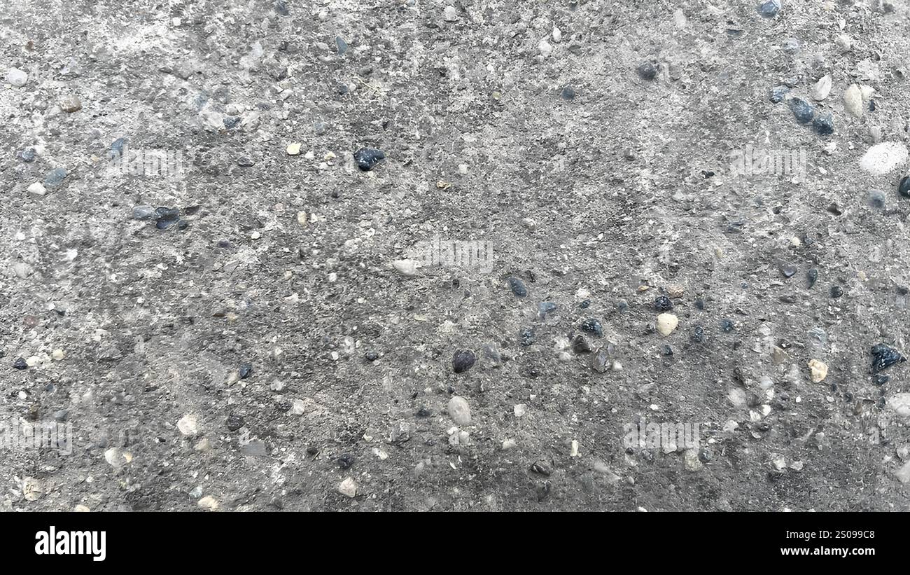 A close-up view of a concrete surface scattered with small pebbles ...