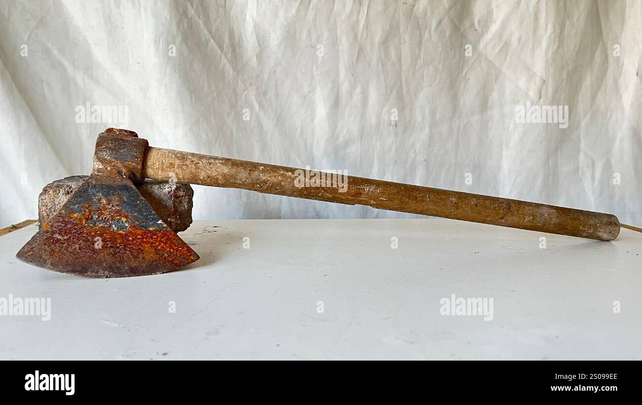 An old, rusty tool rests on a plain white background, highlighting its ...