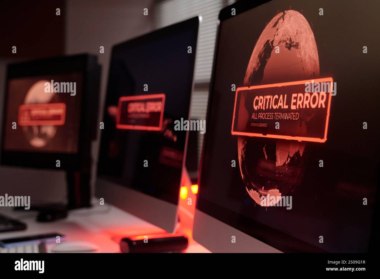Row of desktop computer monitors with critical error on screens standing on workplace of IT ...