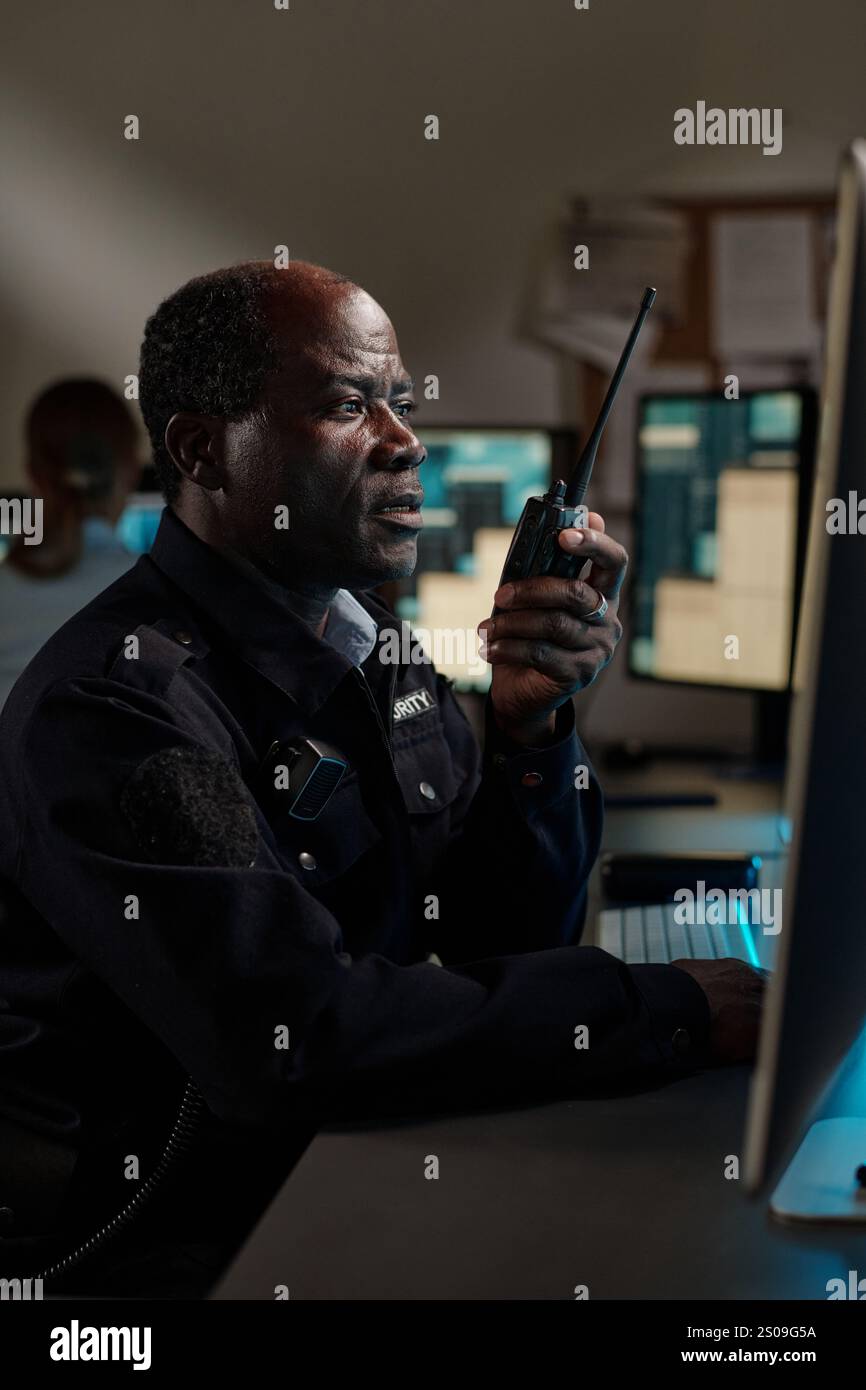 Mature African American security guard in black uniform looking at ...