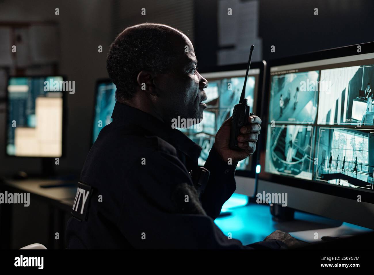Side view of mature African American male guard with walkie-talkie in ...