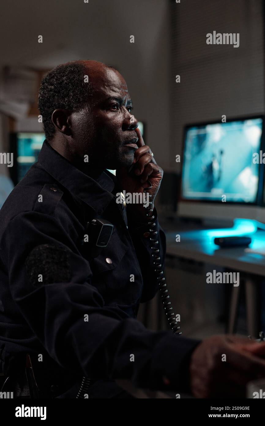 Serious mature man in black uniform of security guard sitting by ...