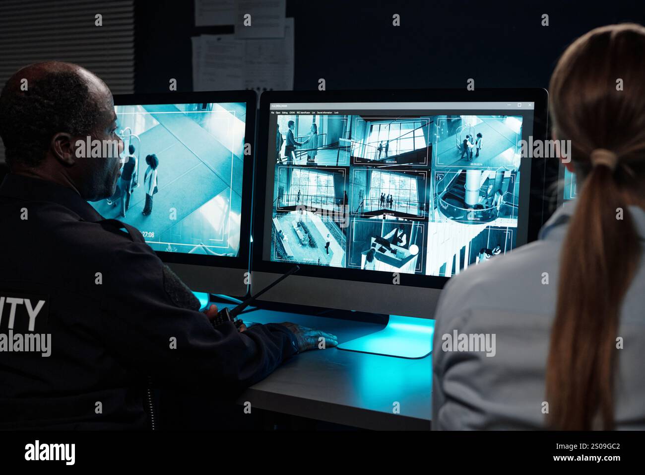 Young and mature intercultural security guards in uniform sitting in ...