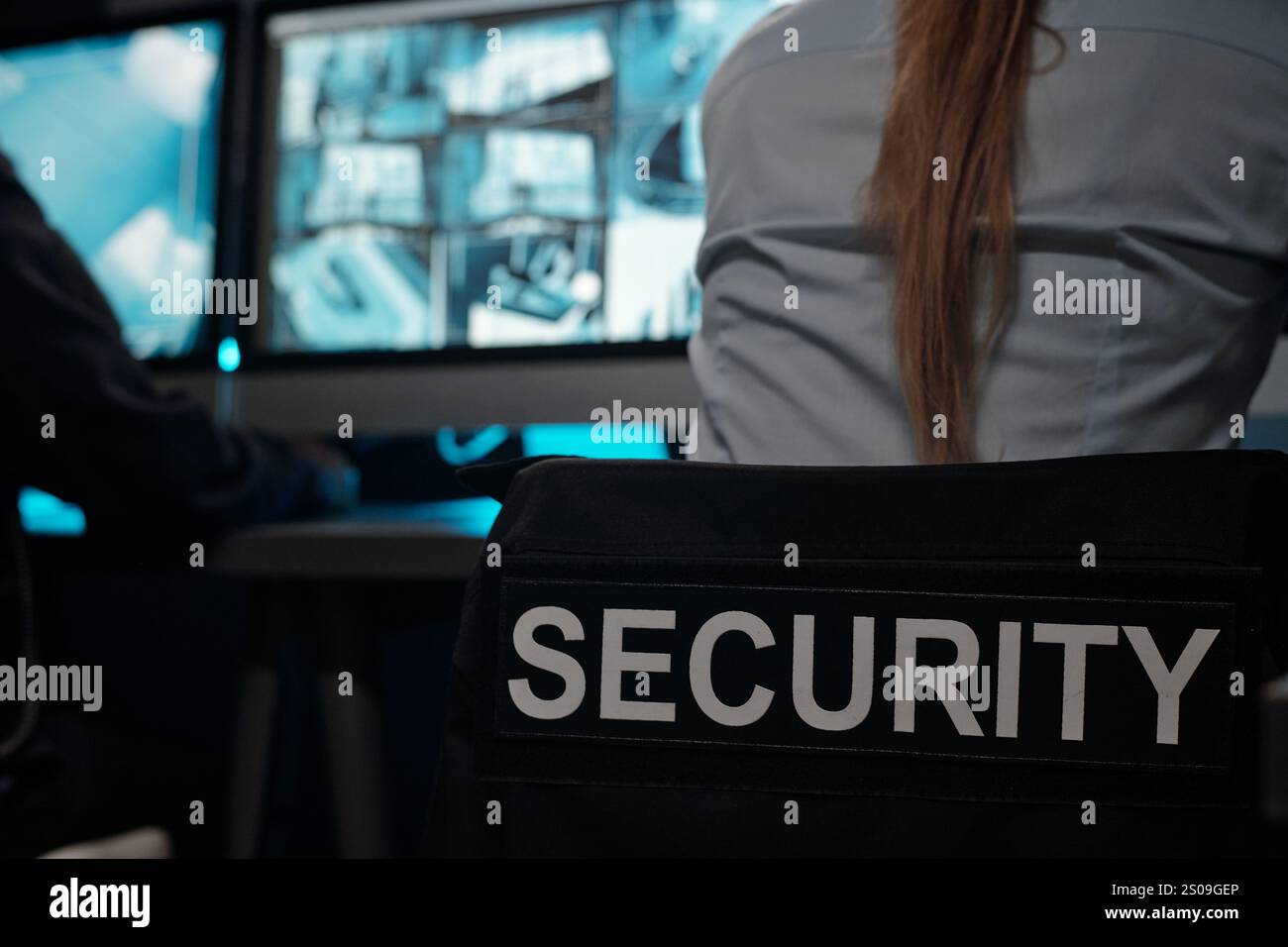 Word security on back of black uniform hanging on chair with young ...