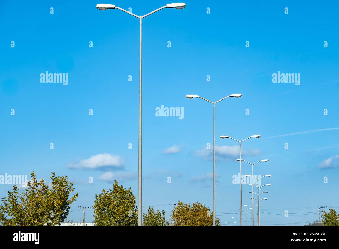A row of street lighting poles on a toll road. City lighting poles off ...