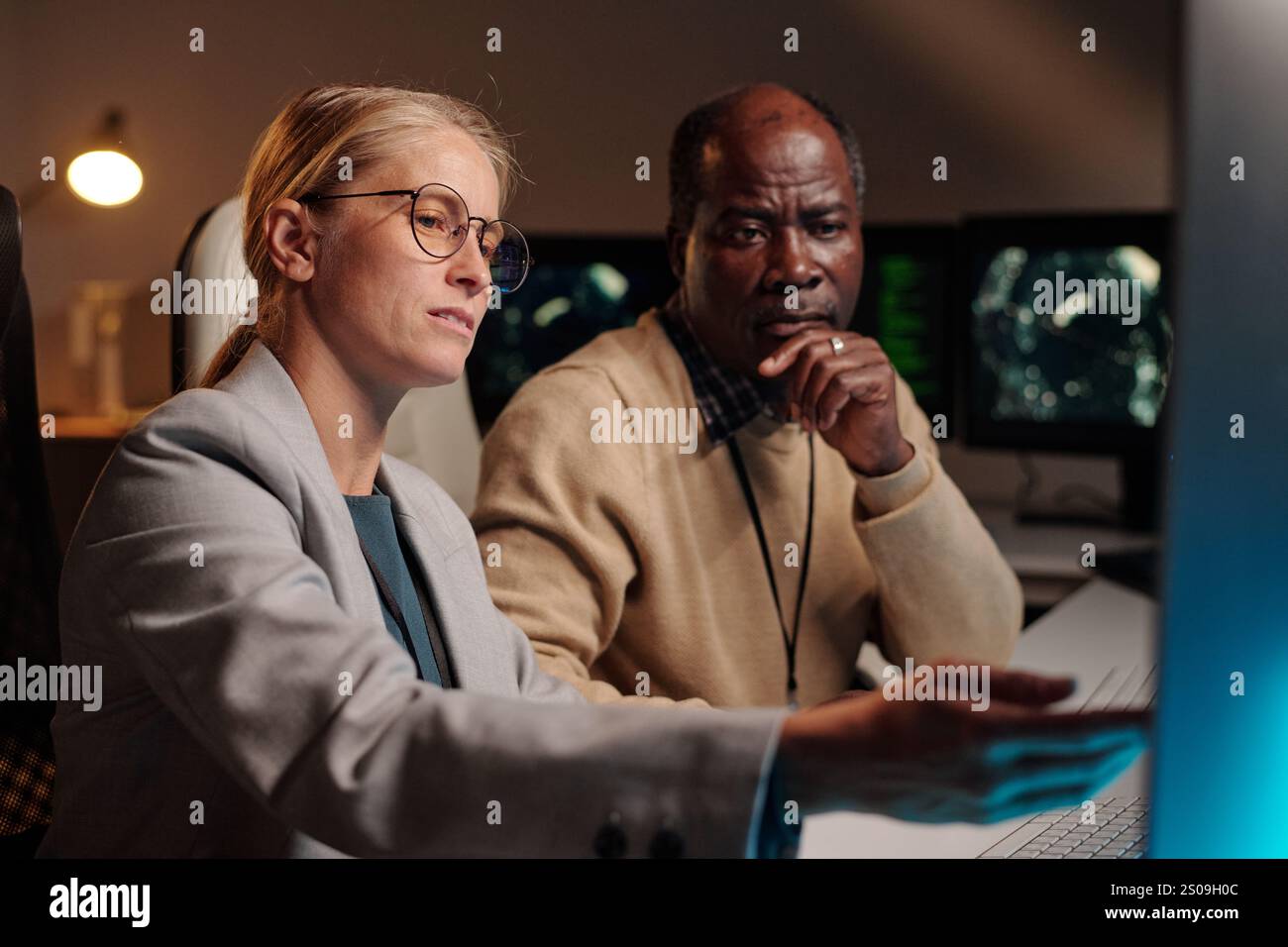 Young confident blond female IT engineer pointing at computer screen ...