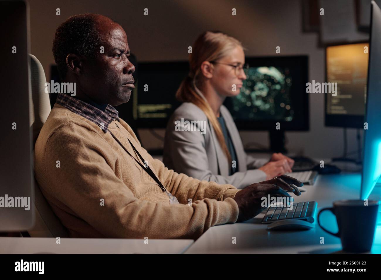 Serious African American IT engineer looking at computer screen and ...