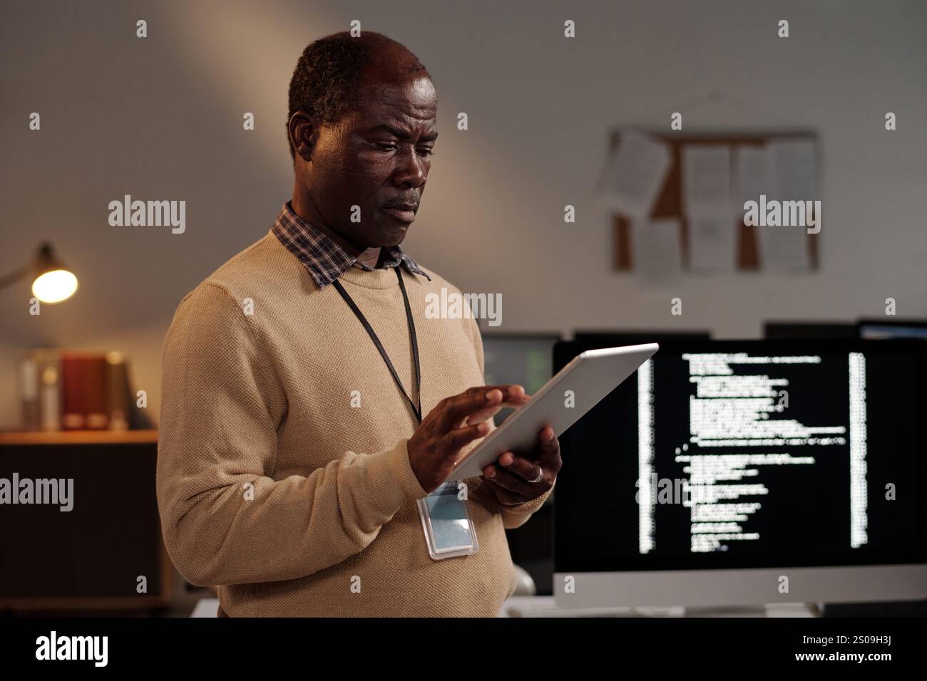 Mature male IT engineer scrolling on tablet screen while decoding ...