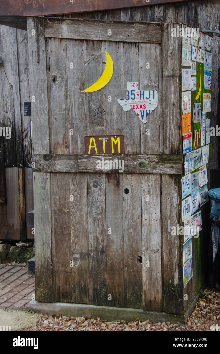 An ATM hides in a fake outhouse in Luckenbach, Texas, covered with old ...