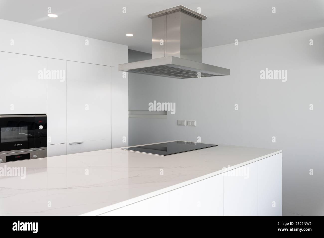 Modern minimalist white kitchen featuring island, cooktop and cooker ...