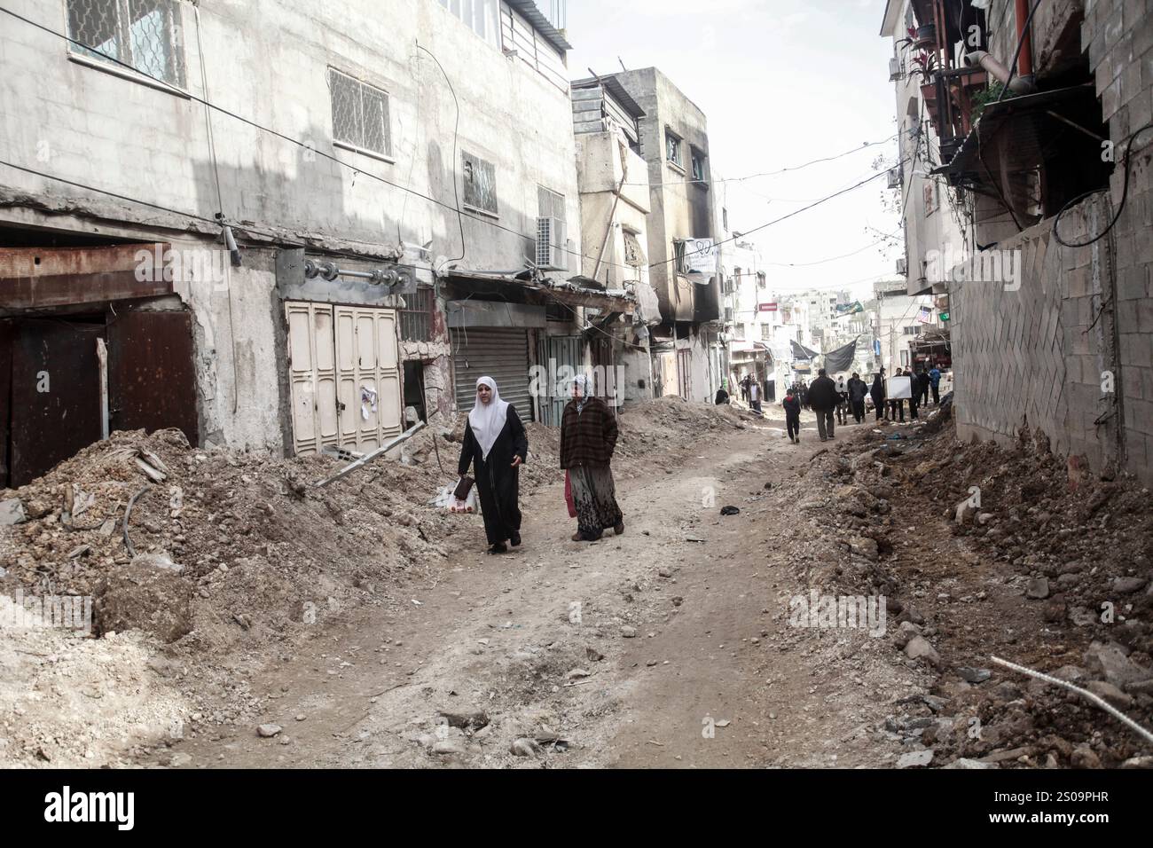 Tulkarm, Palestine. 26th Dec, 2024. Palestinians walk and inspect their ...