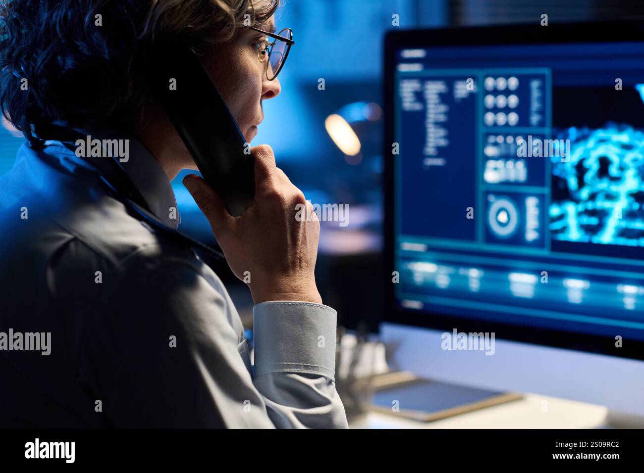 Focus on mature woman in uniform holding phone receiver by ear and ...