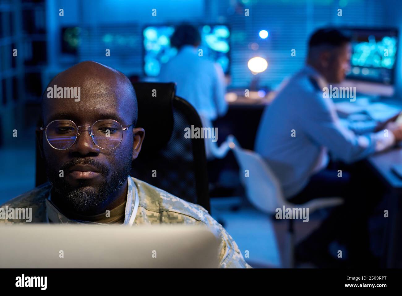 Focus on young African American male officer in eyeglasses looking at ...