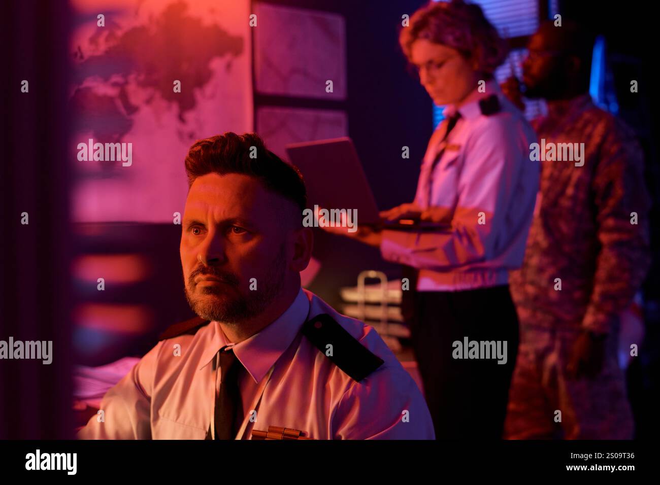 Mature male worker of military command center looking at computer ...