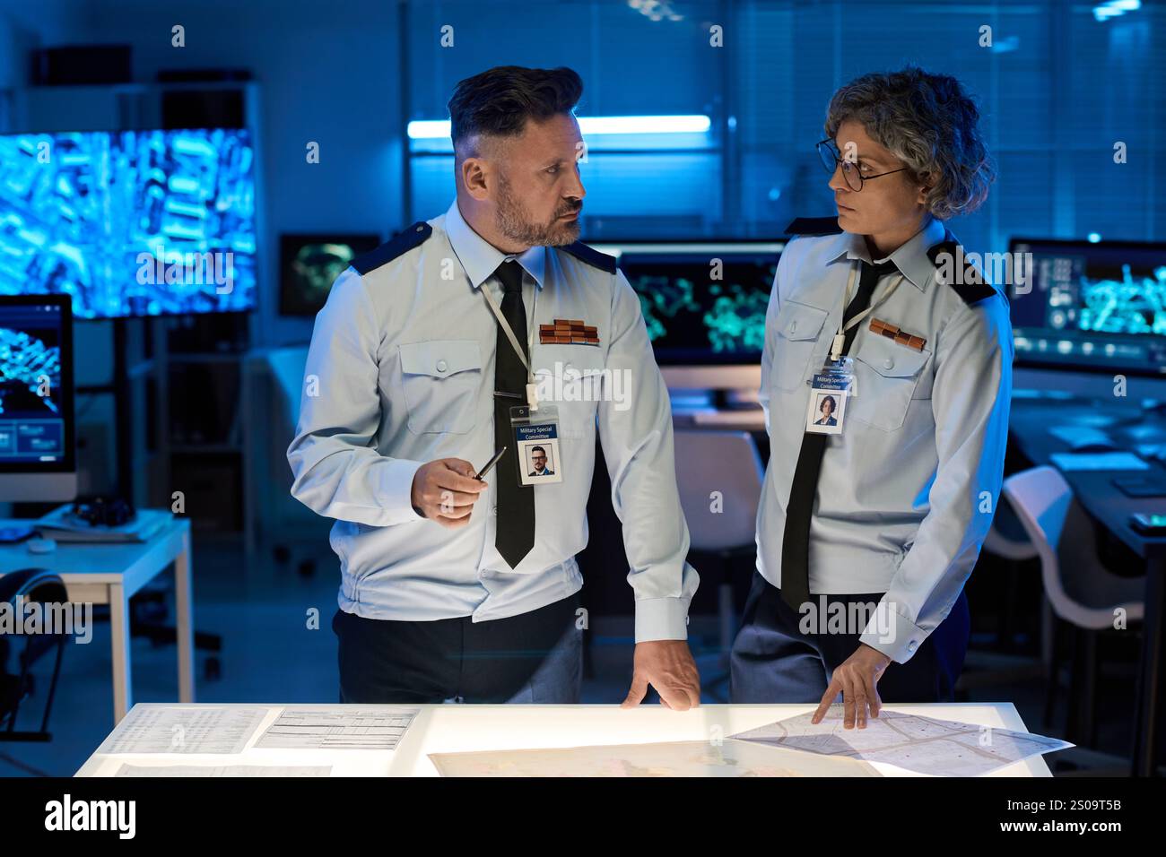 Two confident mature officers in uniform and ties looking at one ...