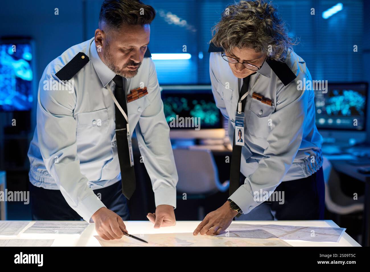 Mature male and female military officers bending over table with paper ...