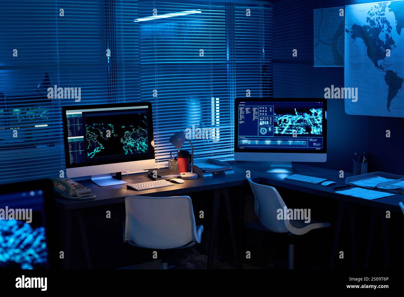 Two desktop computers with graphic data standing on desks in dark ...