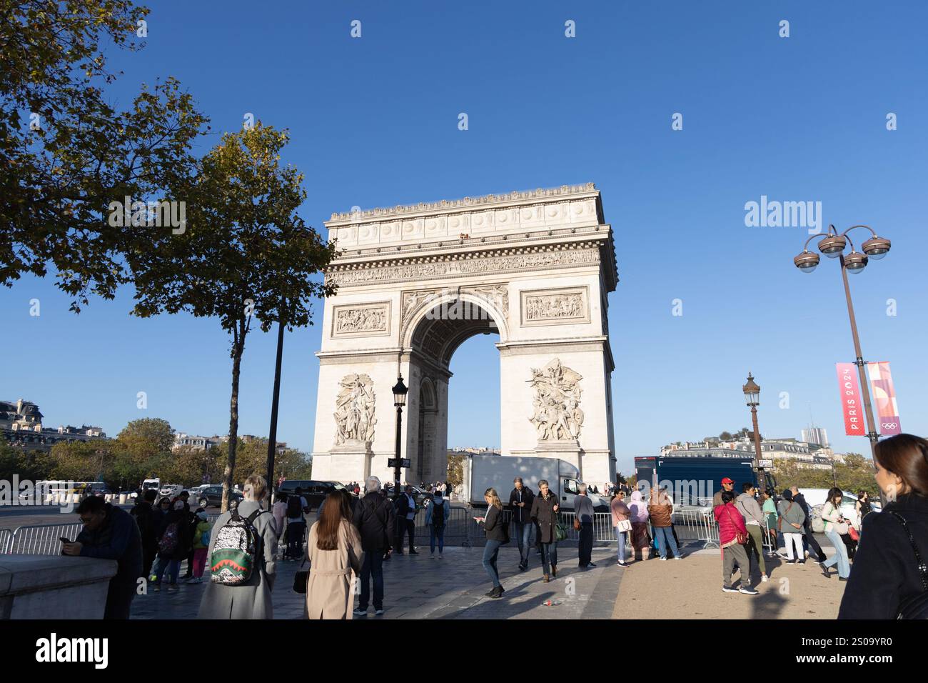 A beautiful scene of the iconic Arc de Triomphe in Paris, with tourists enjoying the clear blue ...