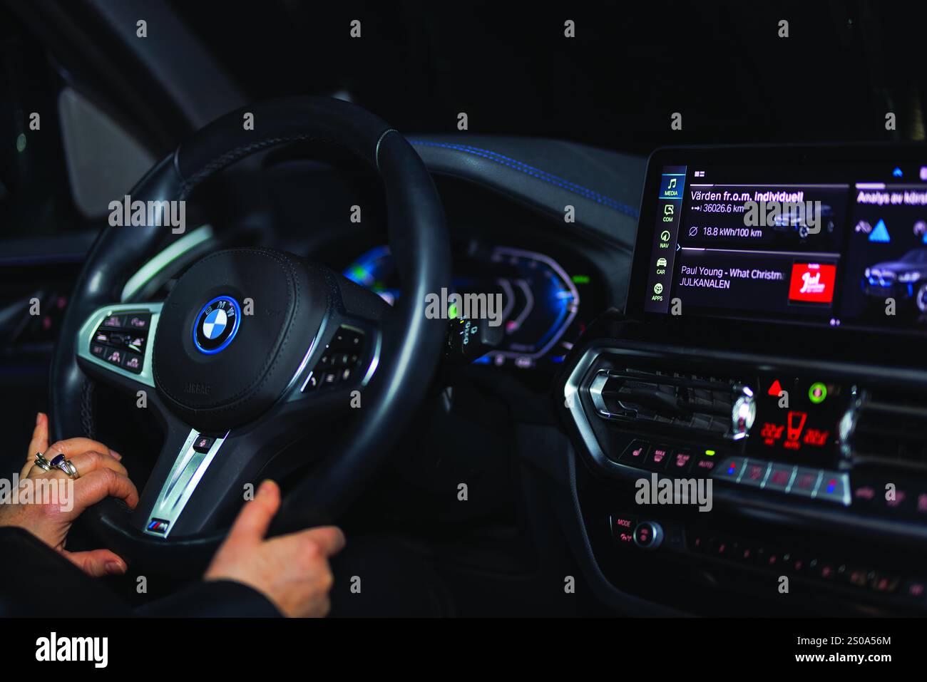 Woman drives BMW iX3 electric car at night with an illuminated ...