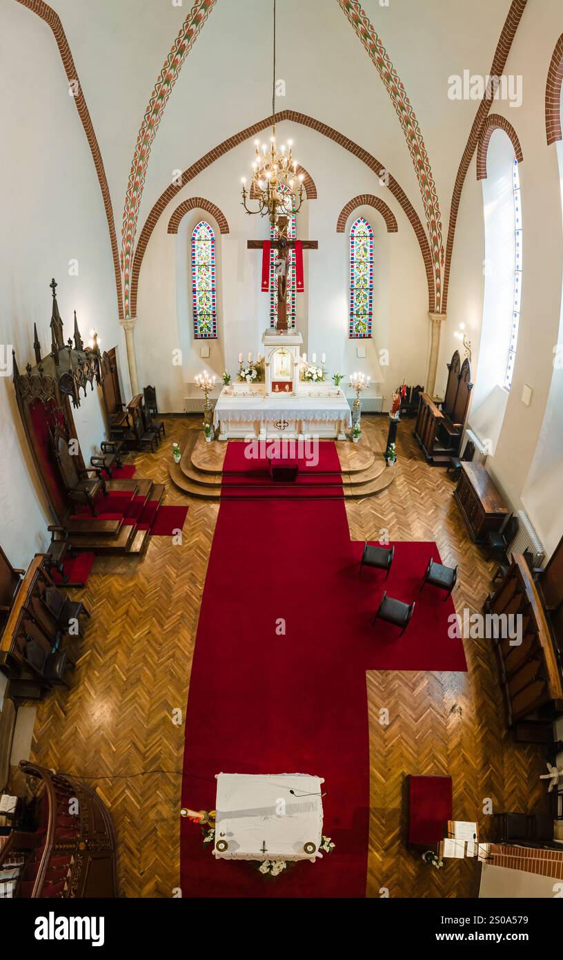 The cathedral interior features a high arched ceiling, stained glass ...