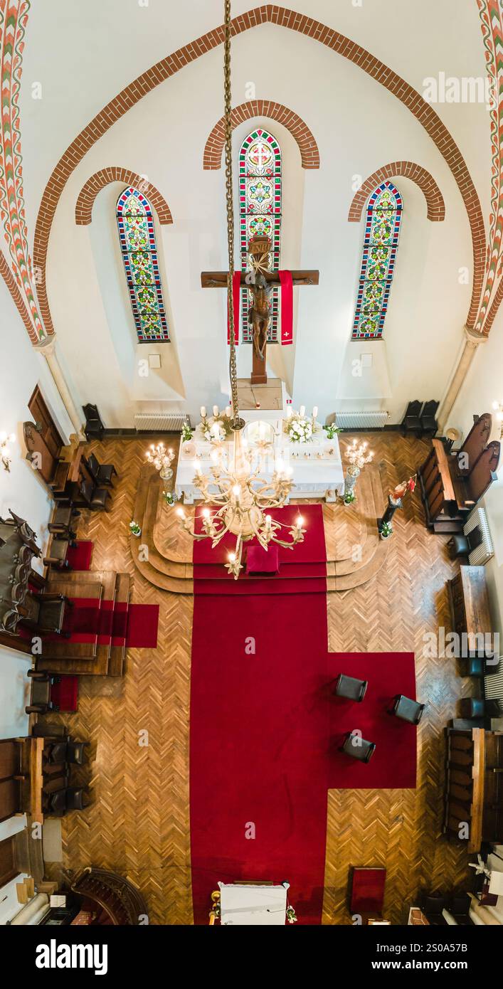Aerial view of a church interior featuring a red carpet leading to an altar with floral ...