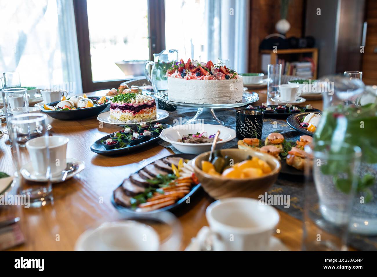 A dining table is filled with a variety of dishes, including a cake ...