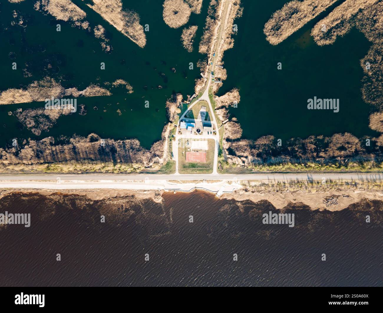An aerial view shows a narrow land strip with a road dividing a water ...