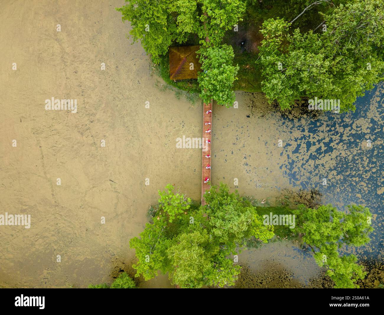 An aerial perspective shows a wooden bridge crossing water, leading to ...