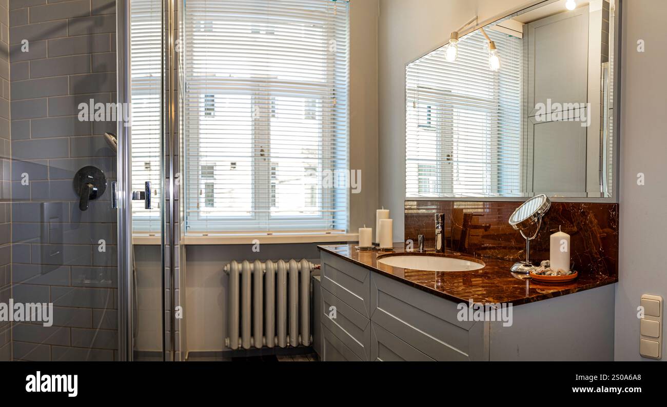 A contemporary bathroom features a large mirror above a marble ...