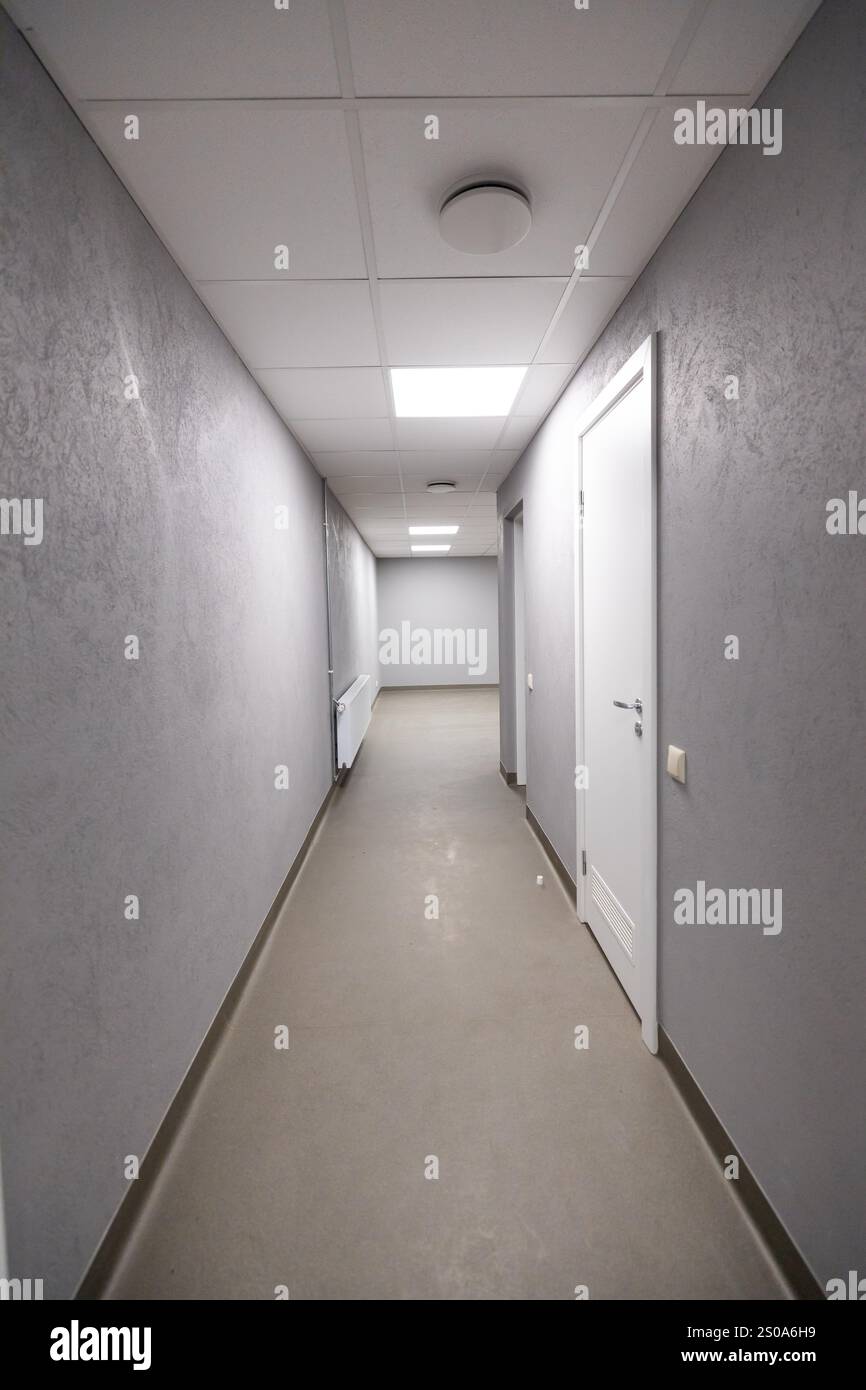 A long corridor with gray walls, light floor, and recessed lighting ...