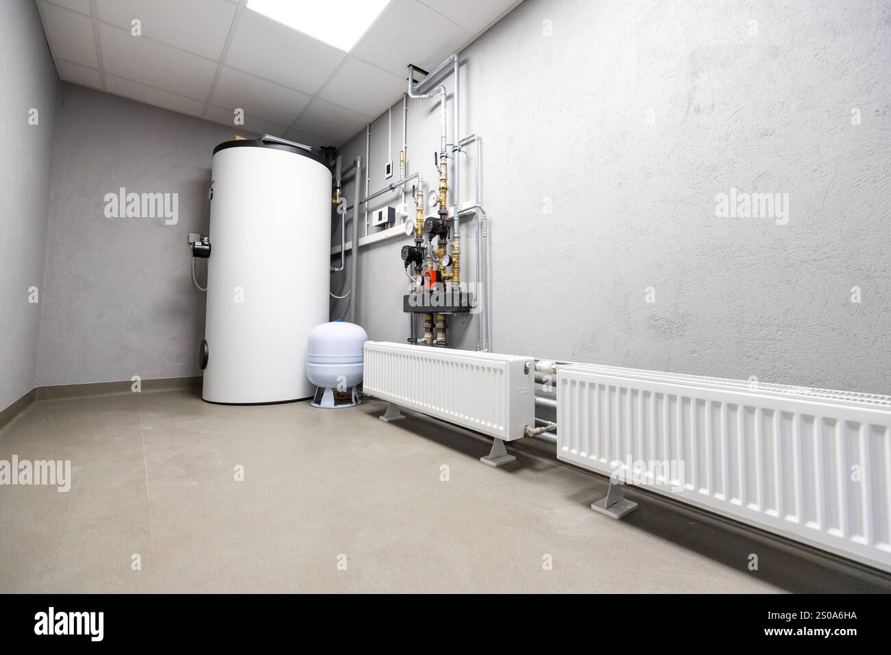 Interior view of a utility room featuring a large white water heater ...