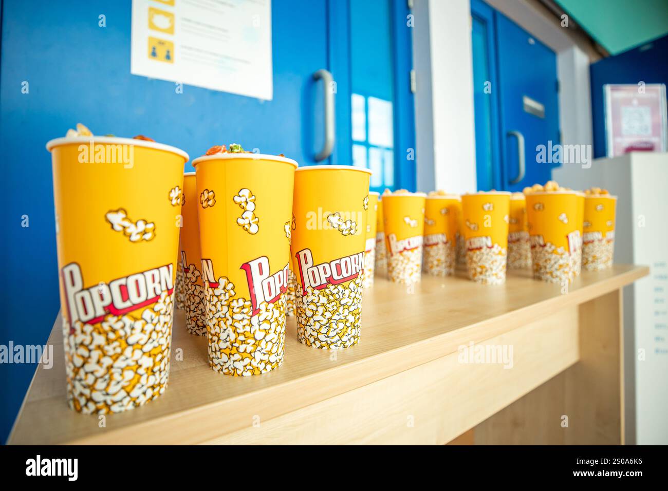 Bright yellow popcorn containers are arranged on a wooden counter, each ...