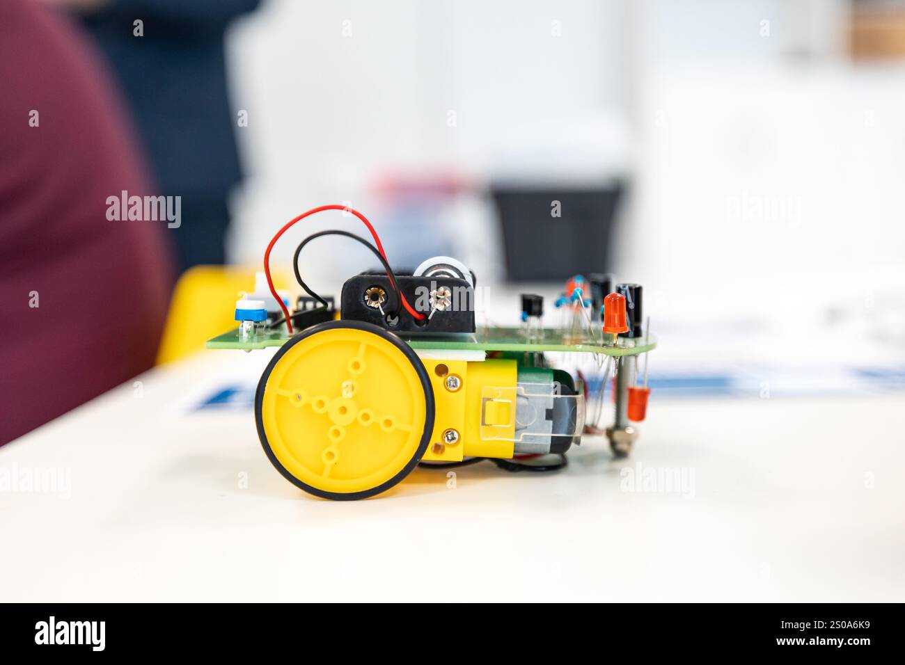 A small homemade robot with bright yellow wheels and visible circuit ...