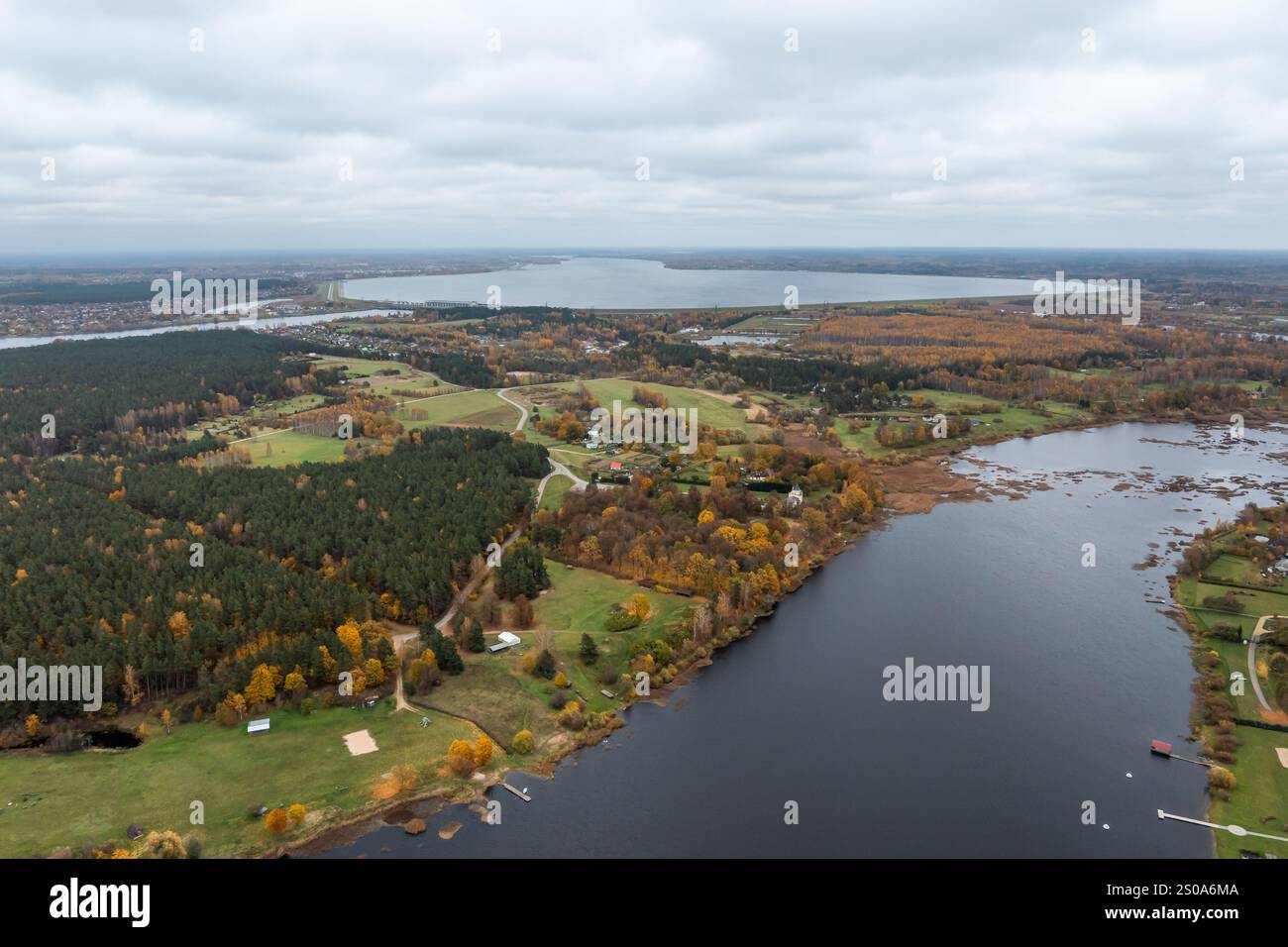 An expansive aerial view shows a large lake surrounded by autumn ...