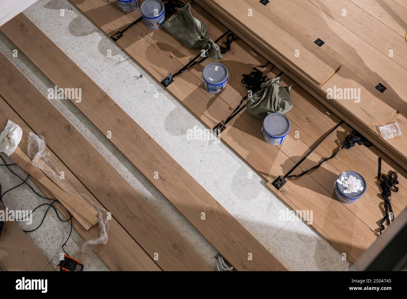 Wooden floorboards are laid on a concrete subfloor with clamps and ...